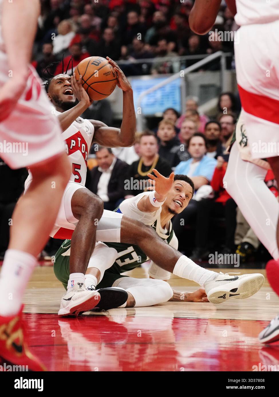 Toronto Raptors' Immanuel Quickley (5) is taken down by Milwaukee Bucks ...