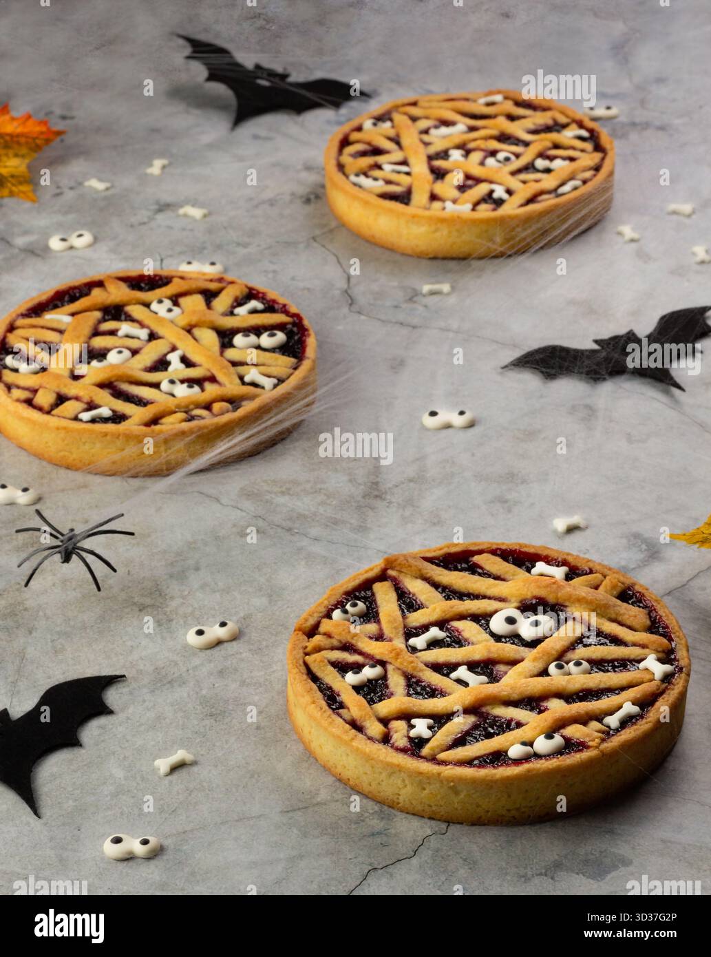Three Halloween tarts sit on a gray surface, decorated with spider webs ...
