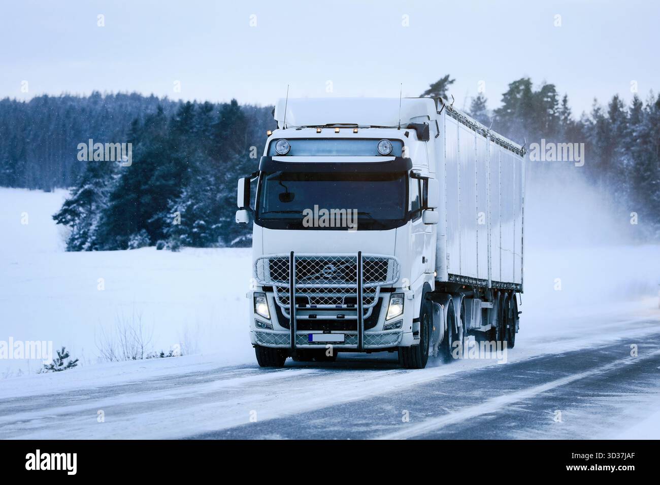 White Volvo FH semi truck transports goods on icy road in winter ...