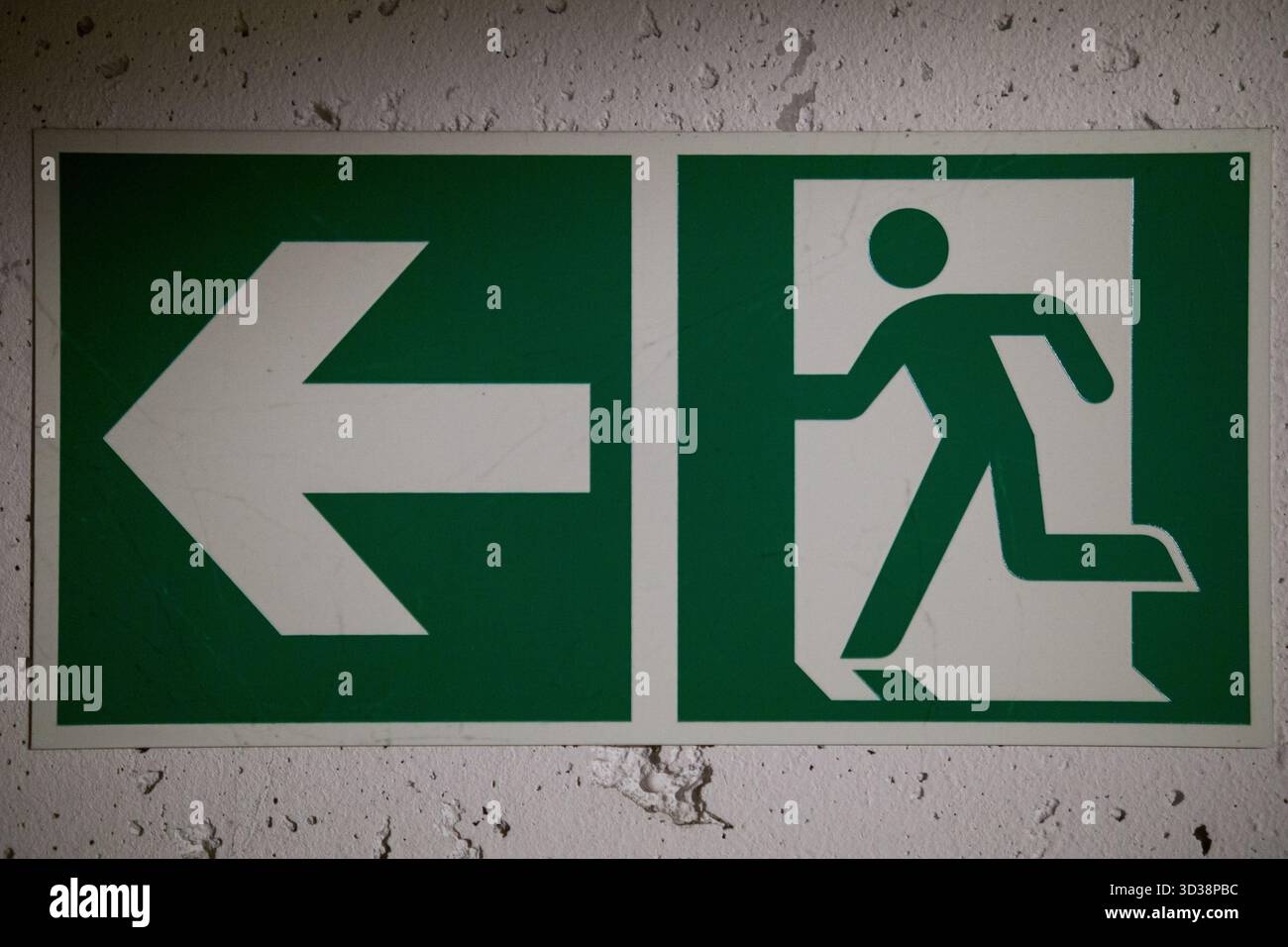 Green emergency exit sign on wall showing direction for evacuation with ...