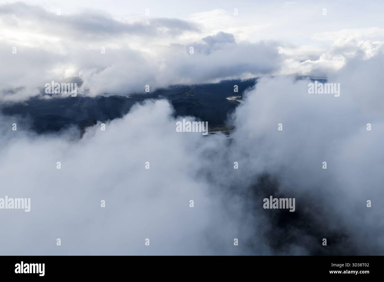 Aerial clouds drift over rugged highlands with a faint river below ...