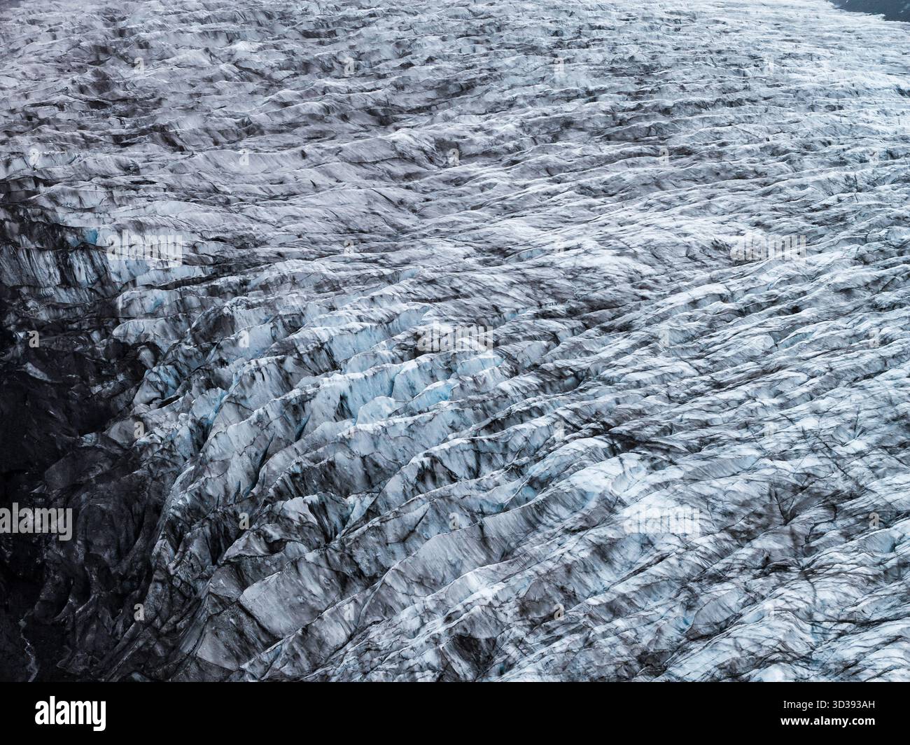 Aerial view of Icelandic glacier crevasses and ash streaked ice ridges ...