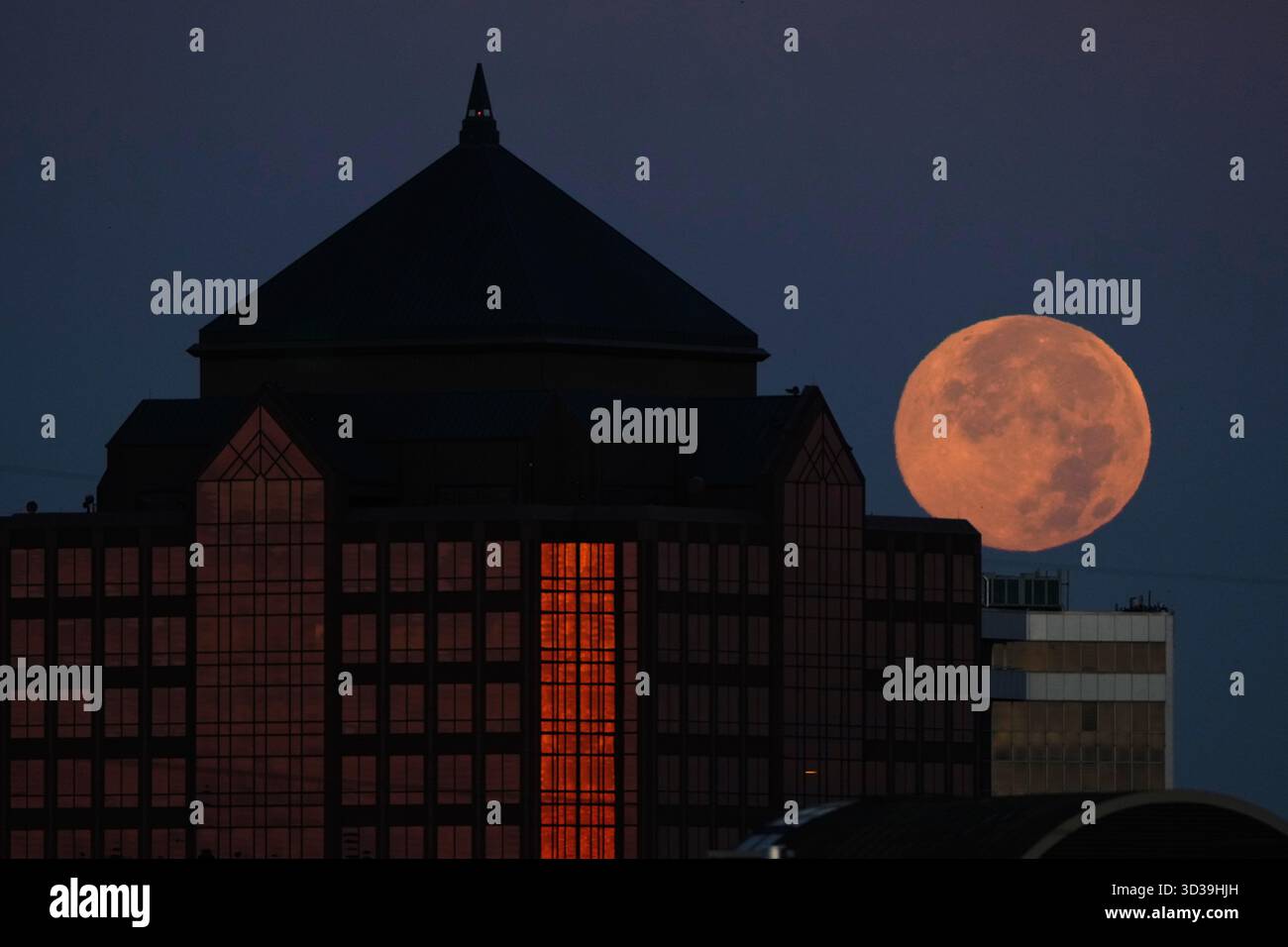 The full beaver supermoon sets beyond an office building Wednesday, Nov ...