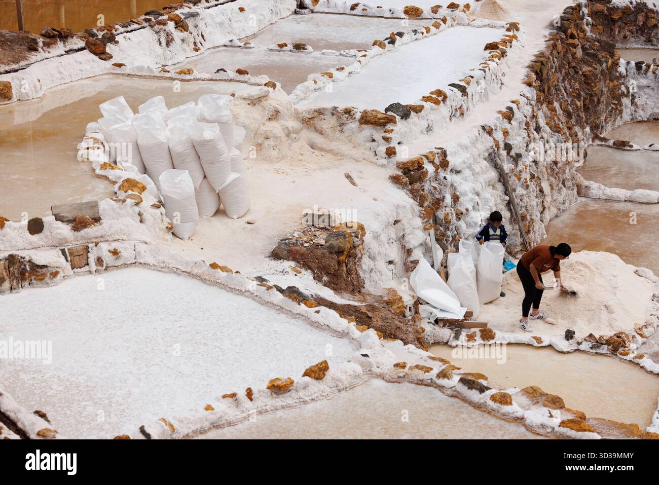 A family packs bags of dried salt weighing about 50kgs at Salineras de ...