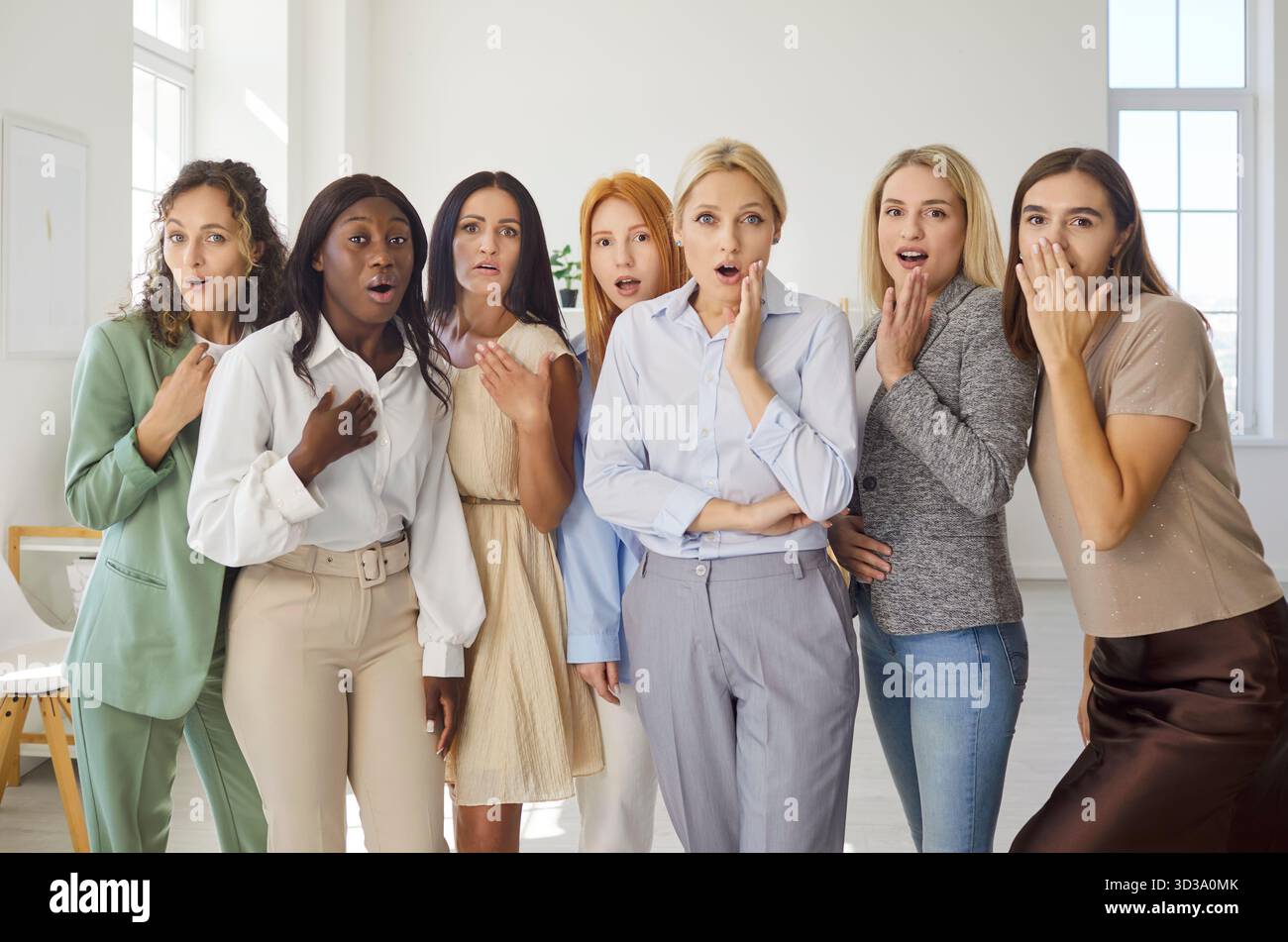 Seven diverse women reacting with amazed shock in bright office group ...
