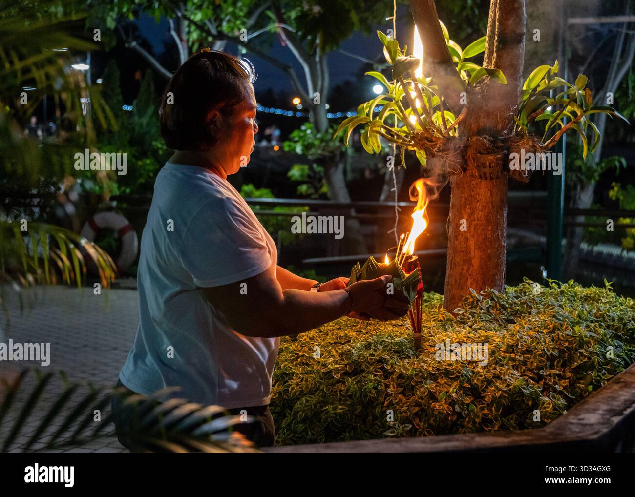 A woman is seen lighting her Krathong basket from a torch at Ladprao 71 ...