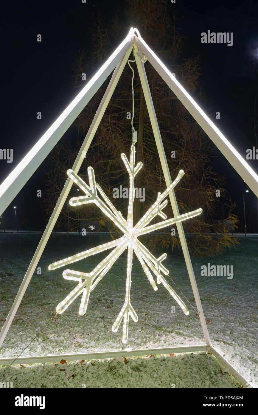 Three modern, illuminated pyramid decorations with snowflake symbols ...