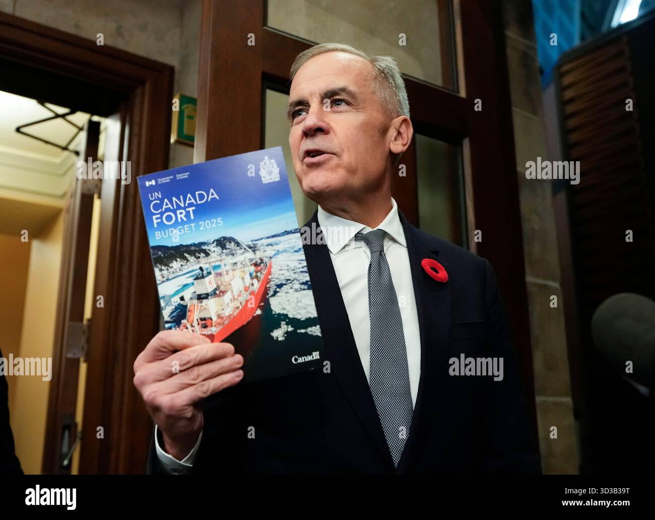 Le premier ministre Mark Carney brandit un exemplaire du budget tandis ...