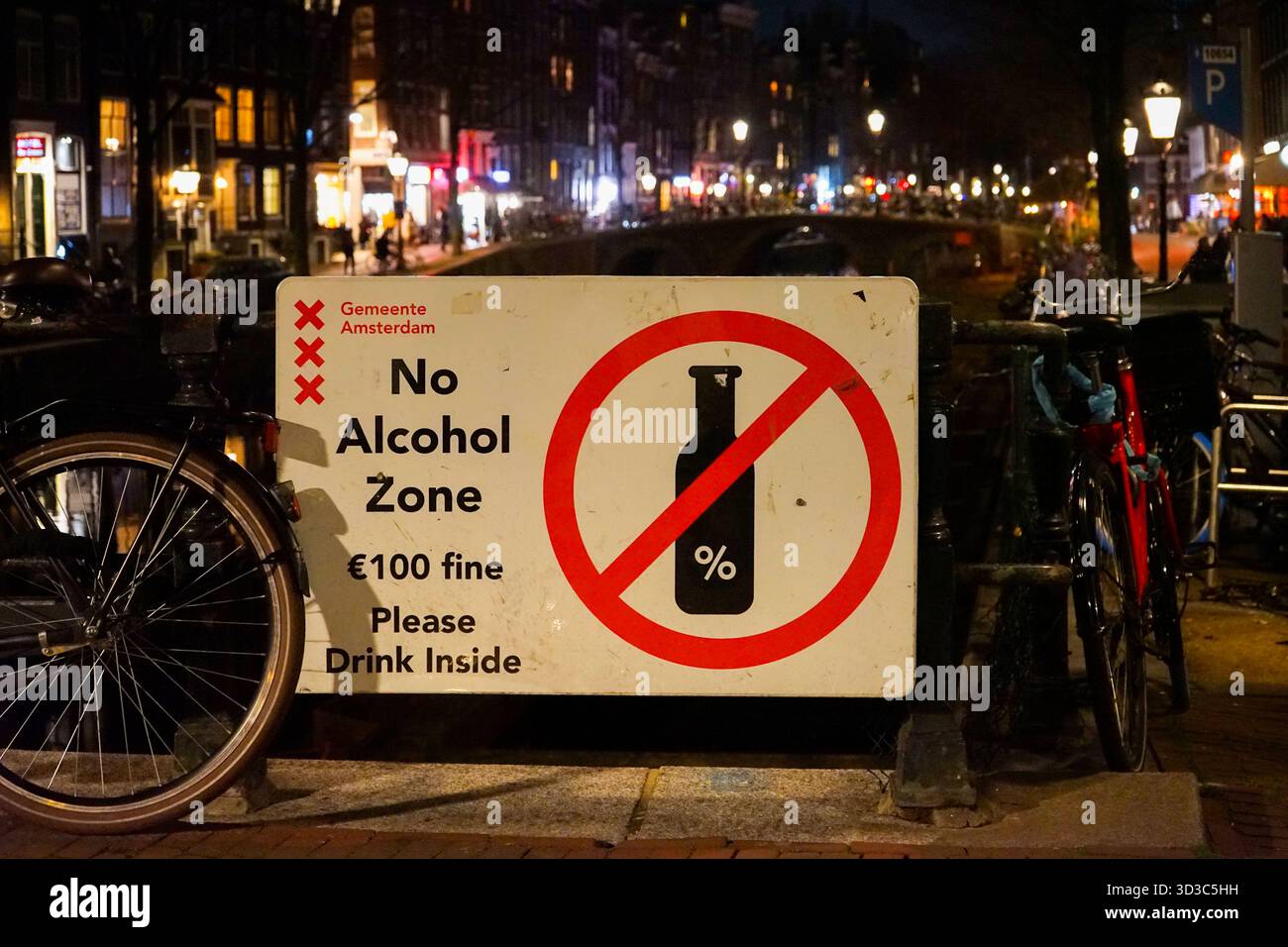 A “No Alcohol Zone” sign along an Amsterdam canal at night, part of ...