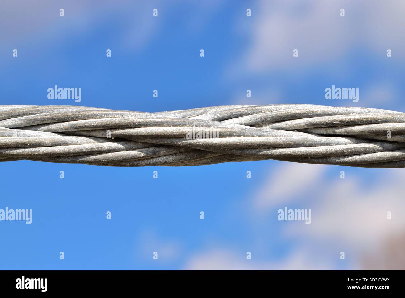Steel wire rope strands aligned under tension with blue sky background ...