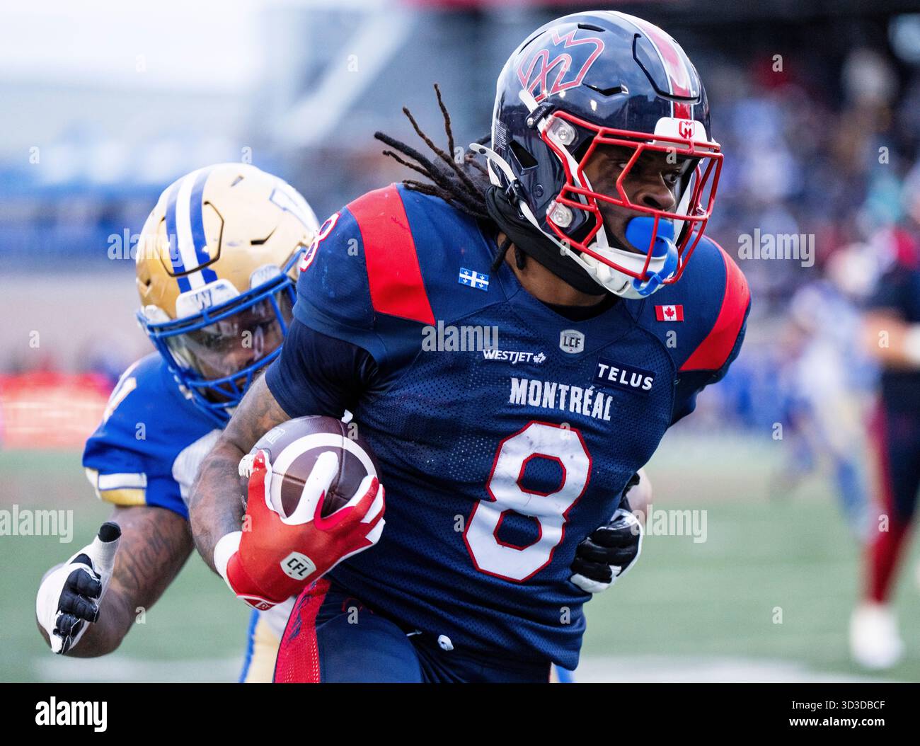 Montreal Alouettes' Stevie Scott III (8) is defended by Winnipeg Blue ...