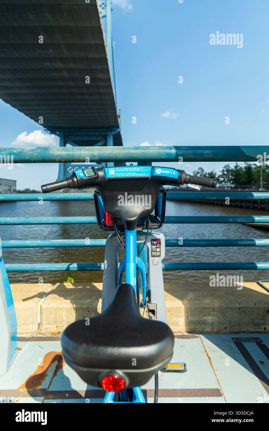 A blue bicycle with a black seat is parked on Benjamin Franklin bridge ...
