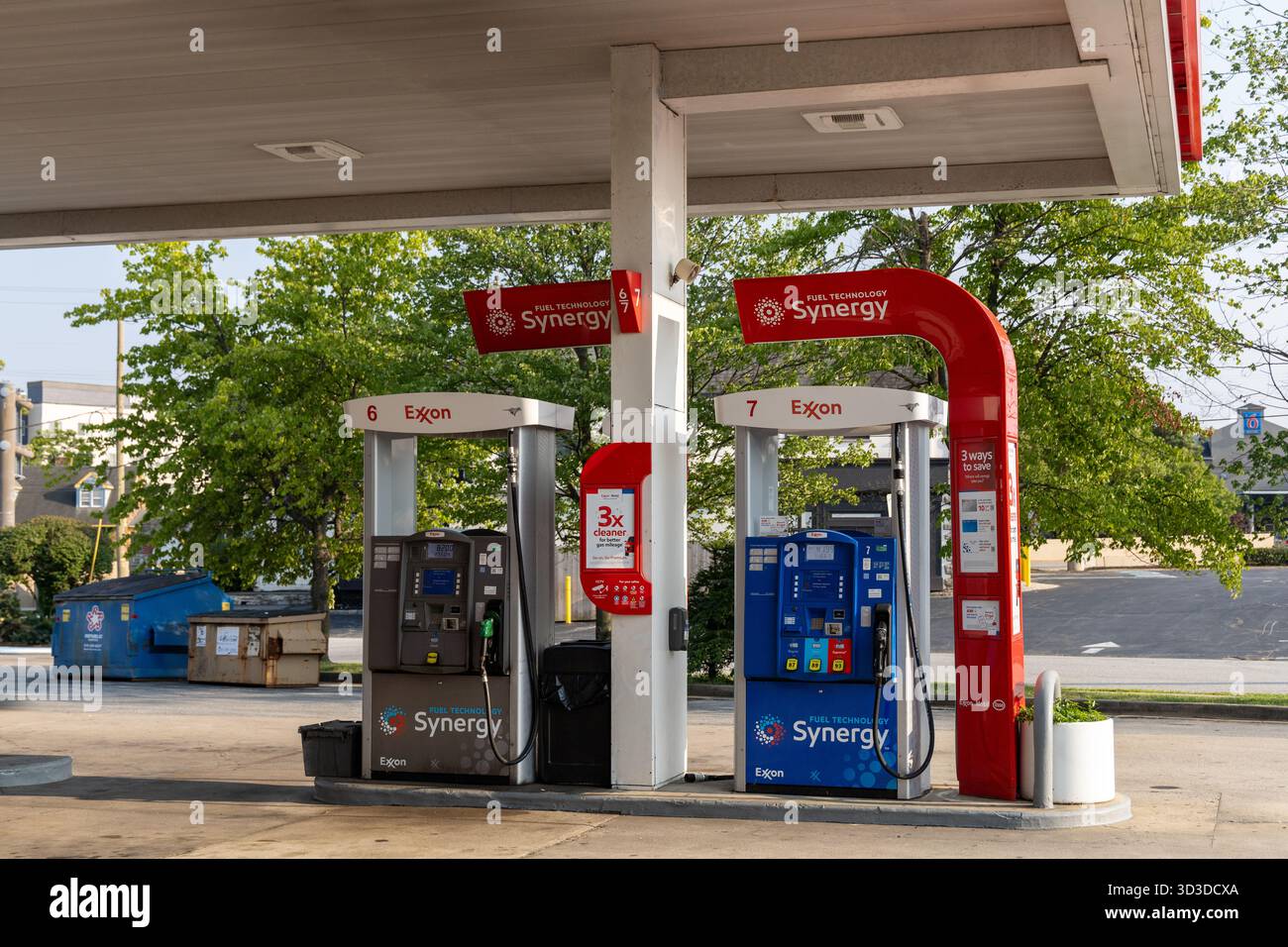 Two gas pumps are at a Synergy gas station. One of the pumps is red and ...