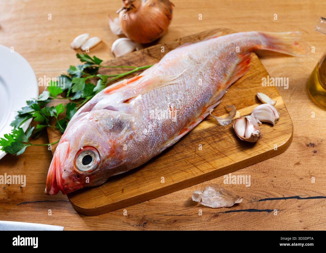 Raw whole red palometa fish with garlic and parsley on desk Stock Photo ...