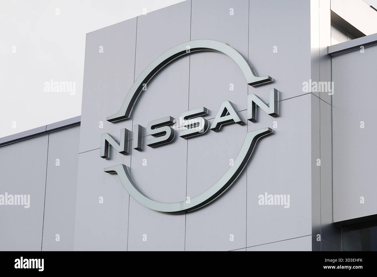 The Nissan logo is displayed on the exterior wall of a dealership Stock ...