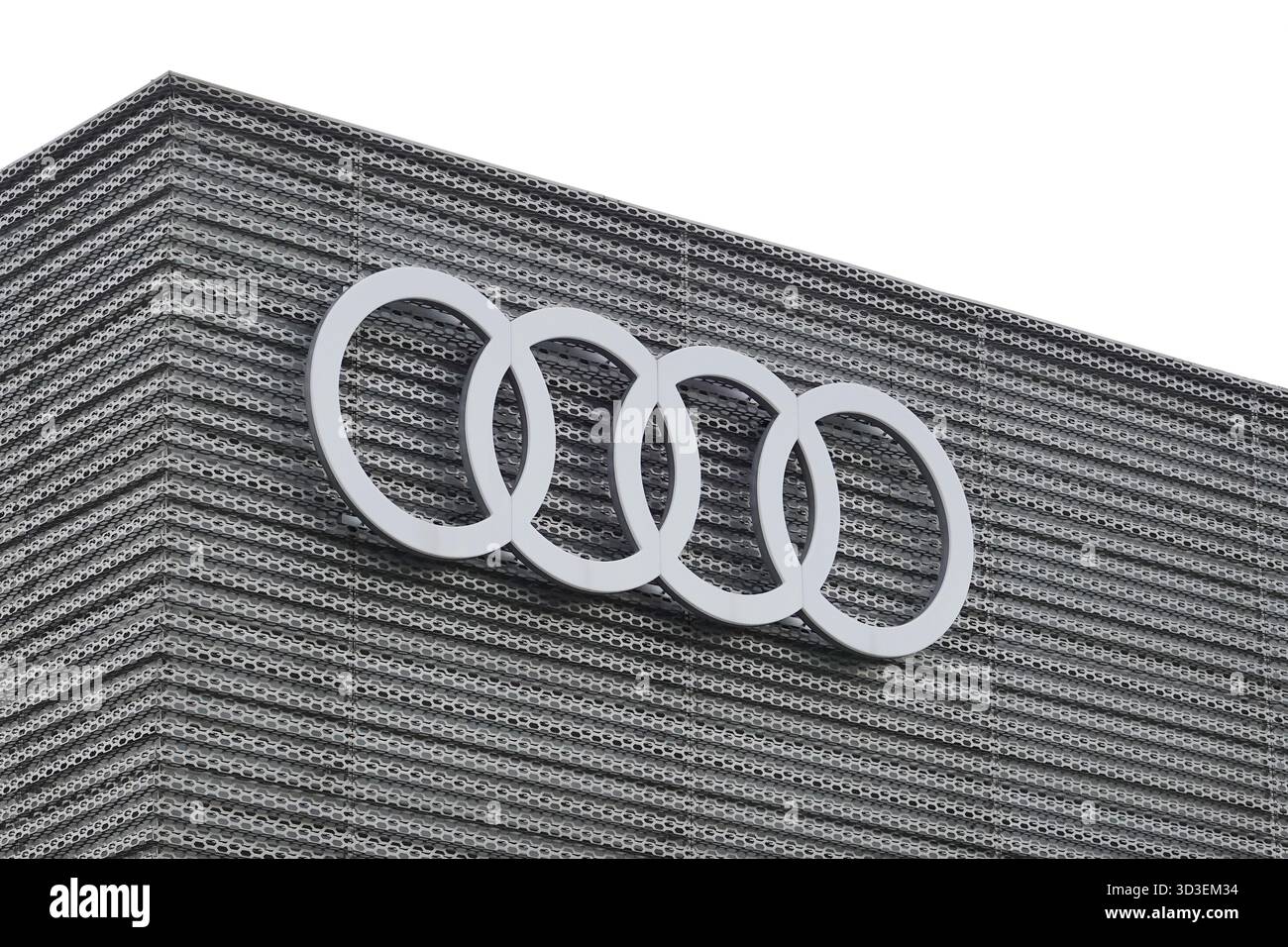 The iconic four-ring logo of Audi is mounted on the corner of a ...