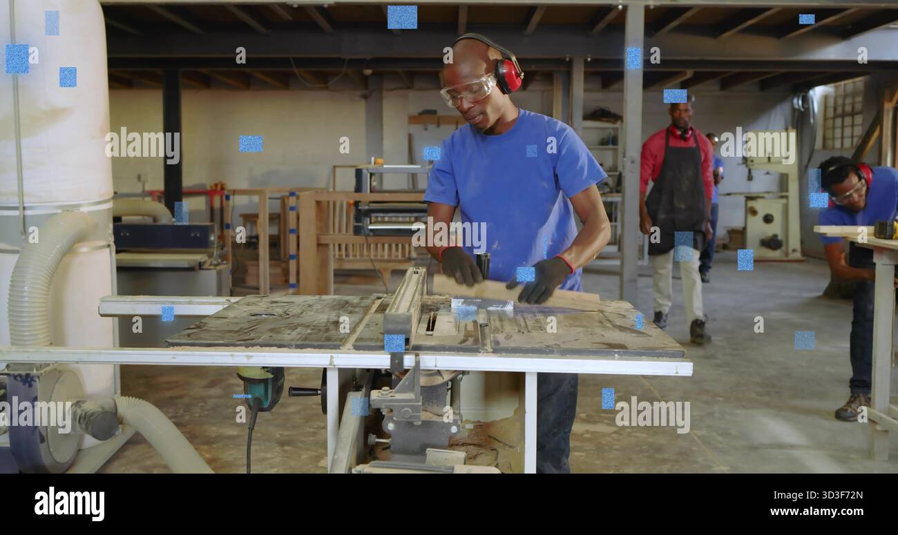Operating carpenter feeding wooden board through table saw in workshop ...