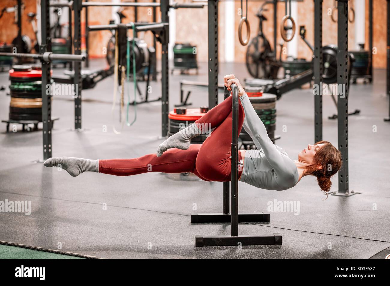 Fitness woman showing strength performing a one leg front lever ...