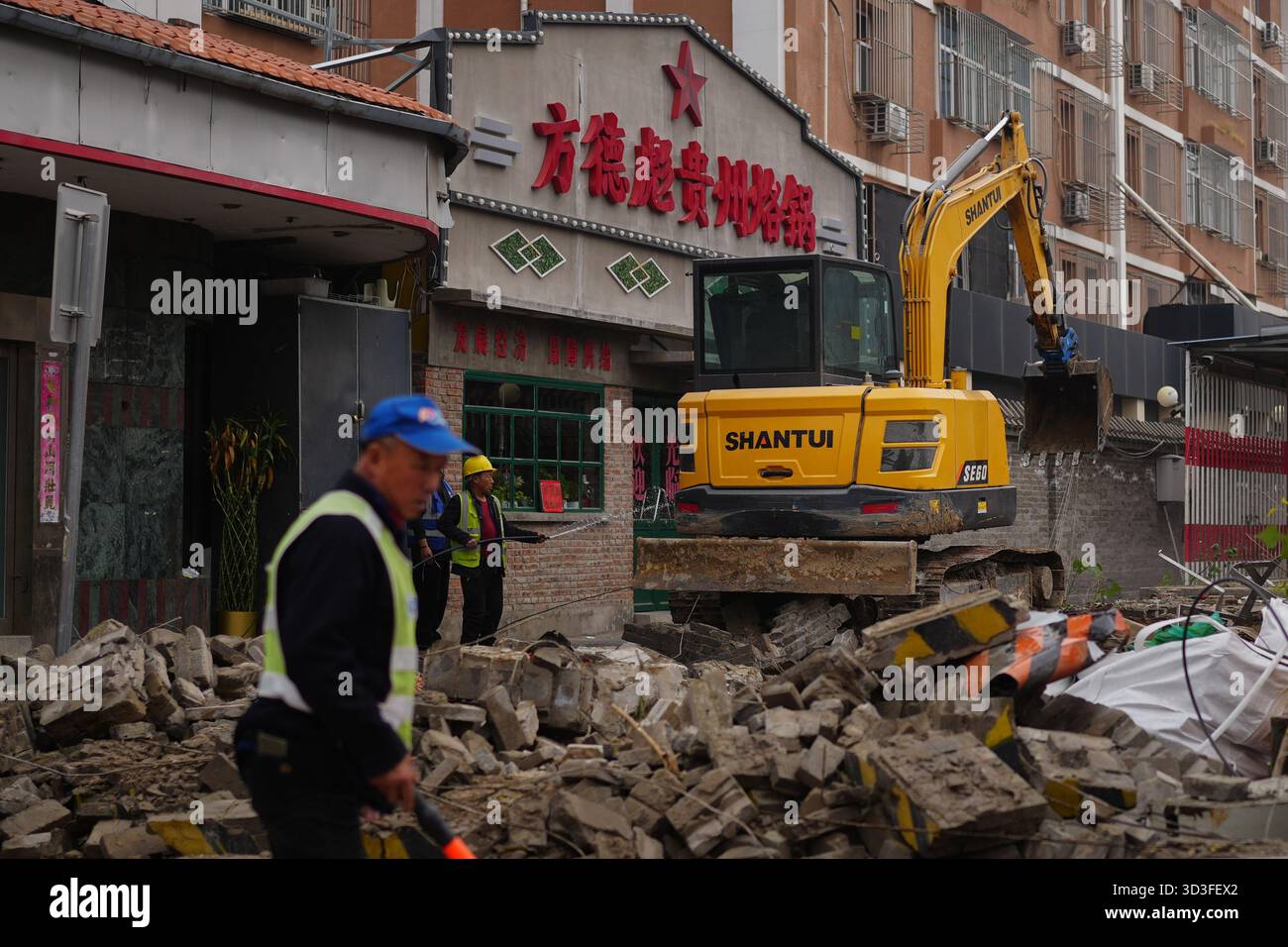 Workers using a heavy duty machine to dismantle a wall near a ...