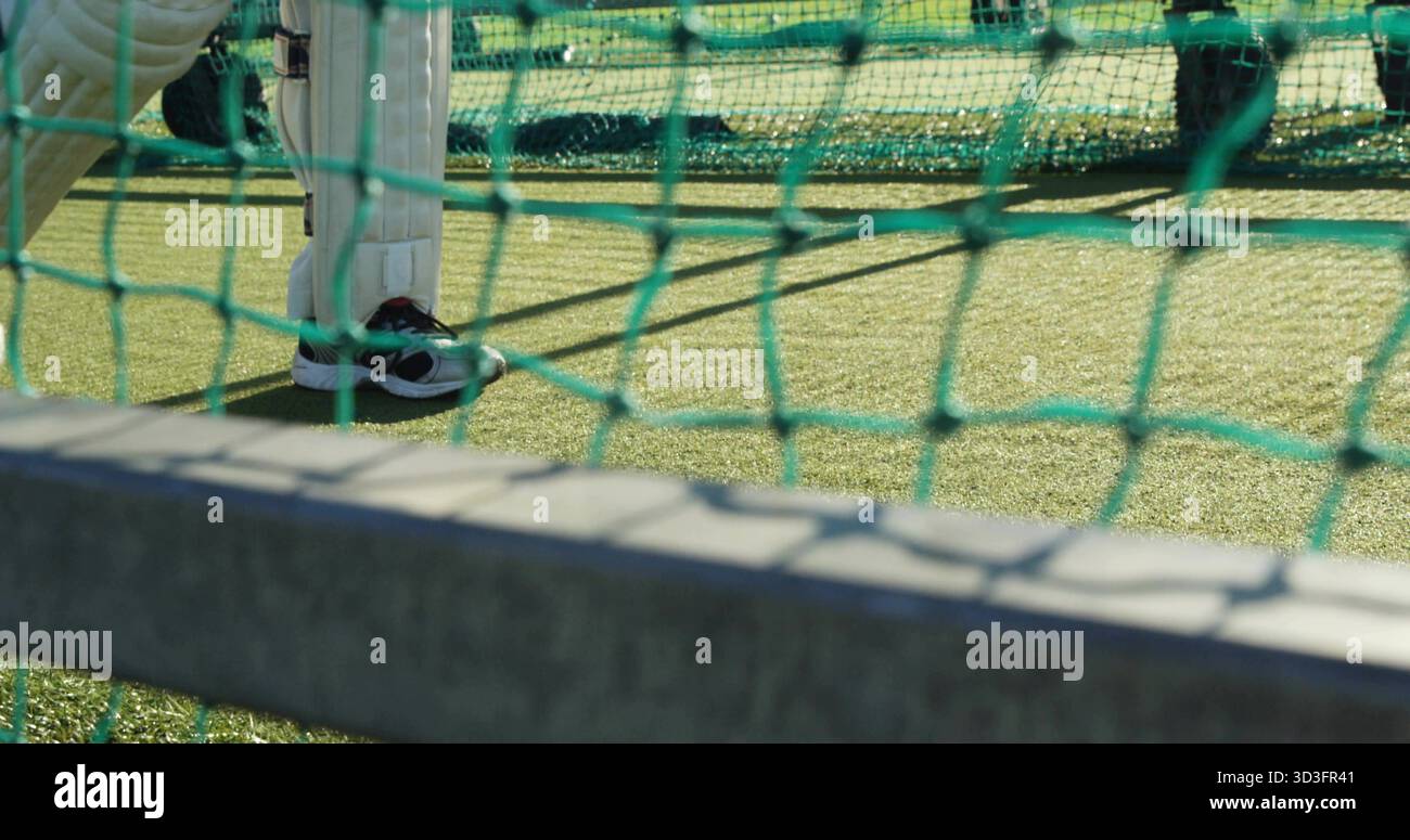 Cricket batter legs standing in net cage on turf, with leg pads, shoes ...