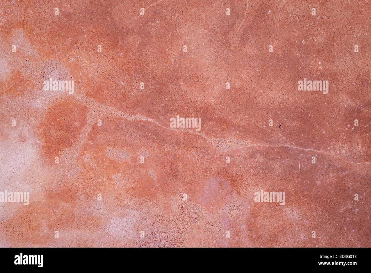 Close-up of a textured stone surface exhibiting earthy red hues and ...