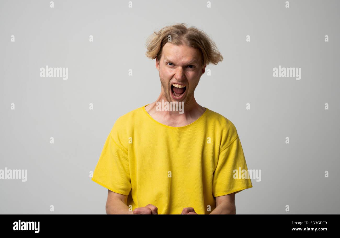 Angry man in yellow shirt screaming with rage and frustration during ...
