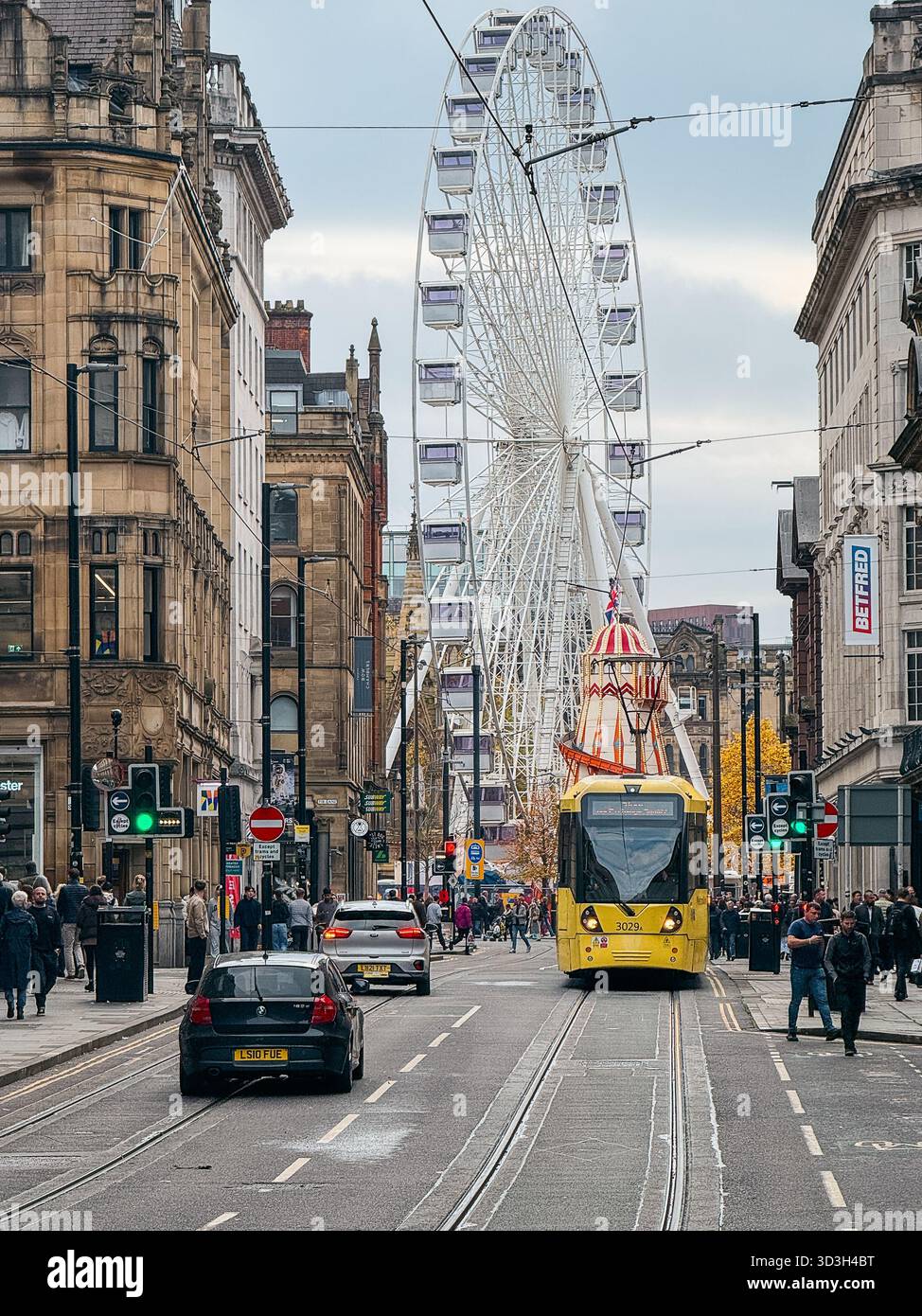 A Bee Network tram in the middle of Manchester City. In the distance is ...
