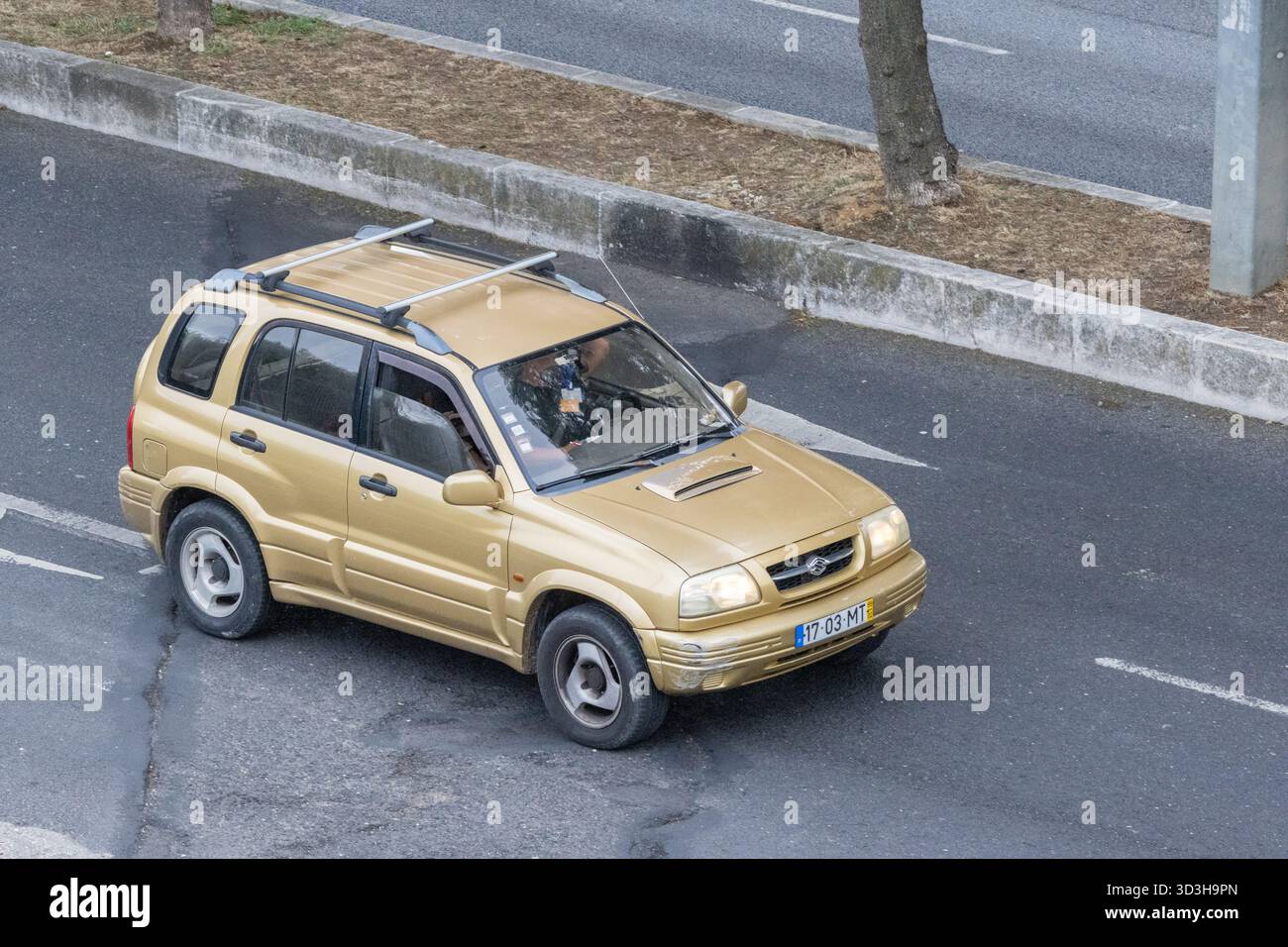 Gold suzuki grand vitara suv driving on an asphalt road with roof rack ...