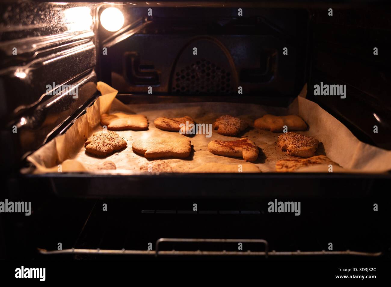 Homemade cookies baking in oven on parchment paper. Warm light ...