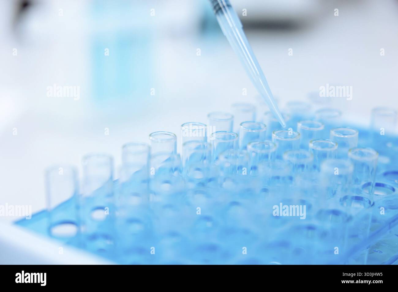 Closeup of unrecognizable scientist dripping blue liquid from pipette ...
