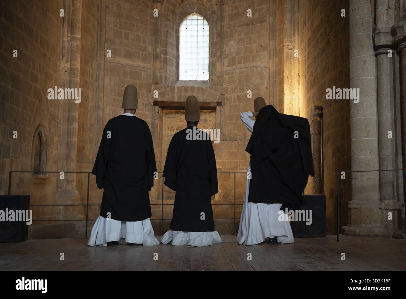 Three sufi dervishes wearing traditional clothes standing in bellapais ...