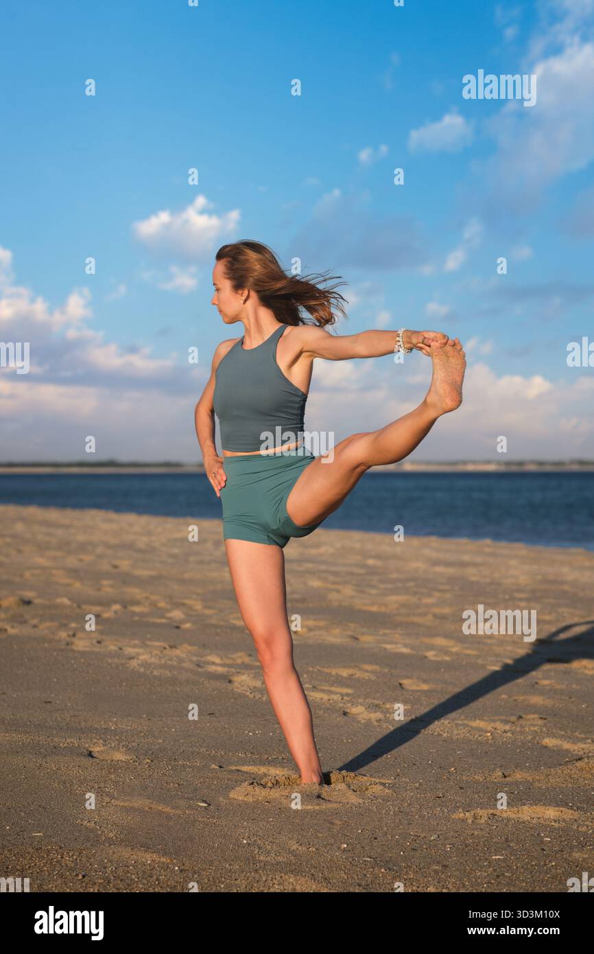 Woman yoga practice at the beach in Utthita Hasta Padangusthasana ...