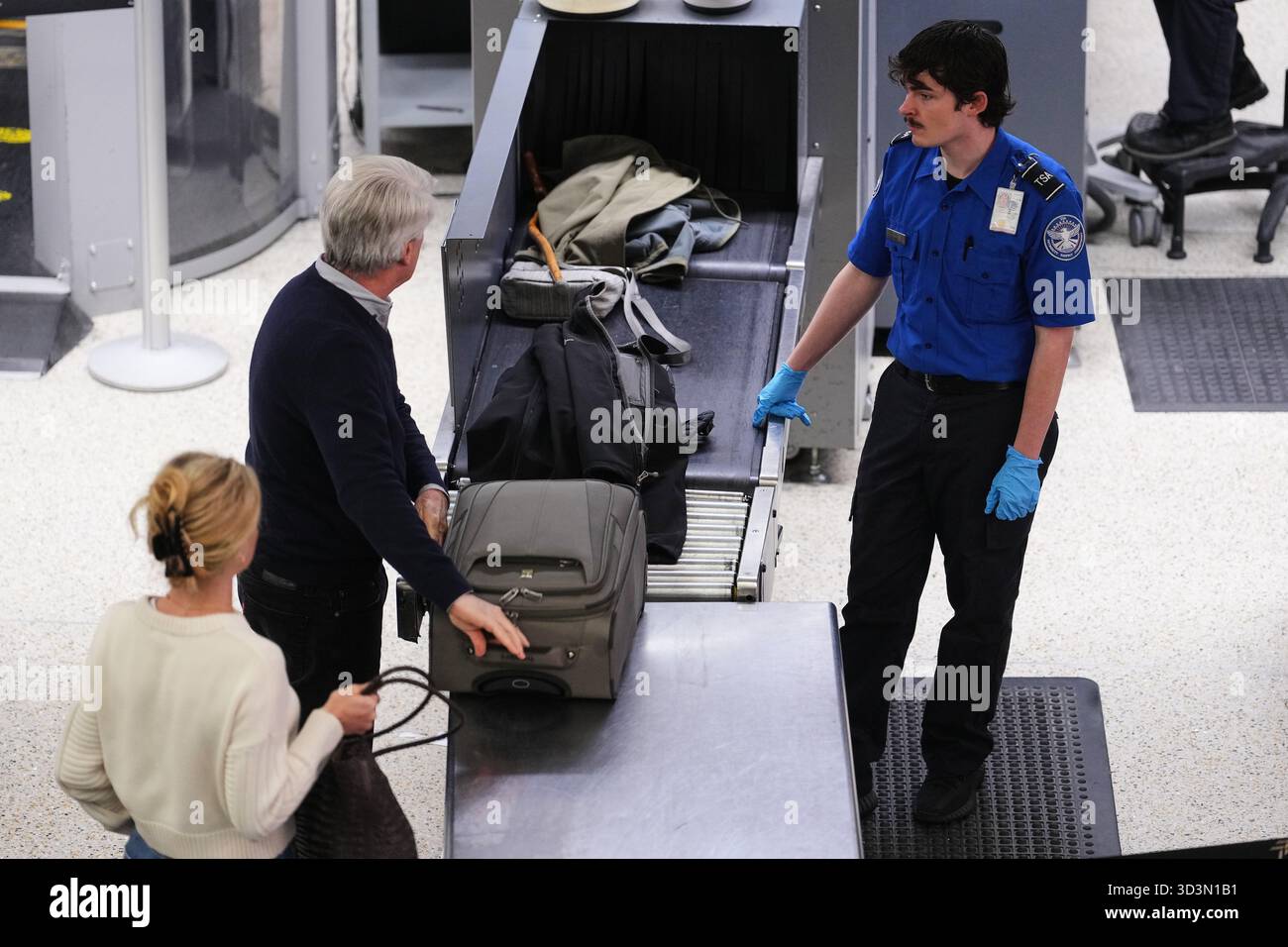 A TSA agent monitors a conveyor belt at a security checkpoint at ...