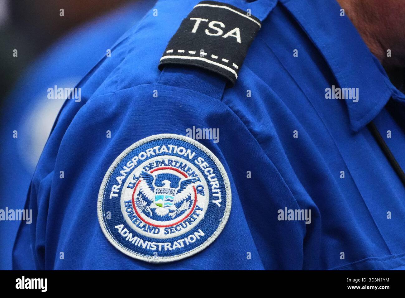 A TSA agent wears a Transportation Security Administration badge while ...