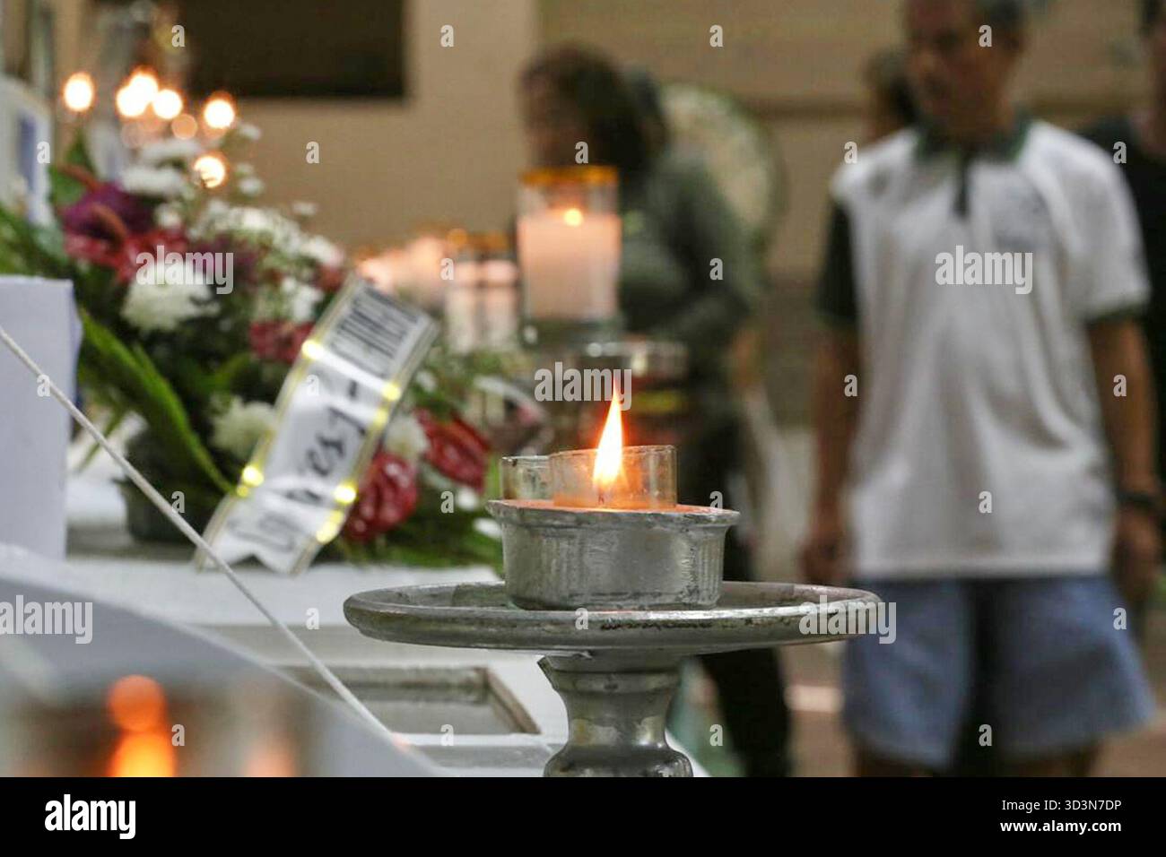 A candle is lit beside coffins at a gym in Bacayan, Cebu province ...