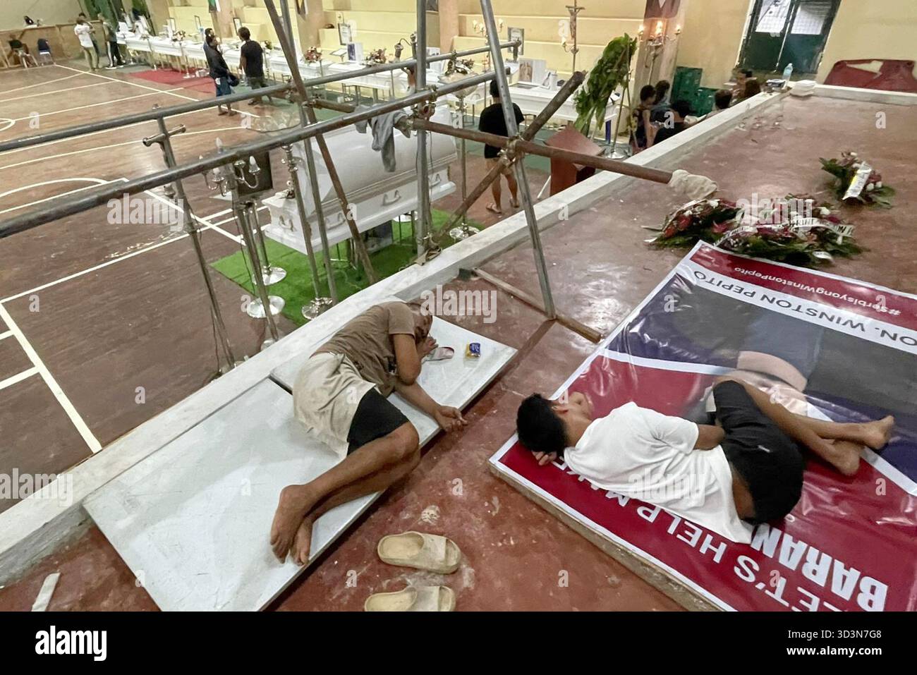 People sleep at a gym where coffins of flood victims lie in Bacayan ...