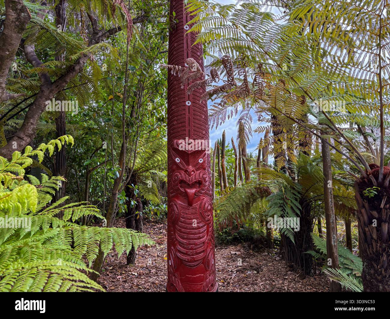 Traditional Māori carving, known as a pou or tekoteko, stands amongst ...