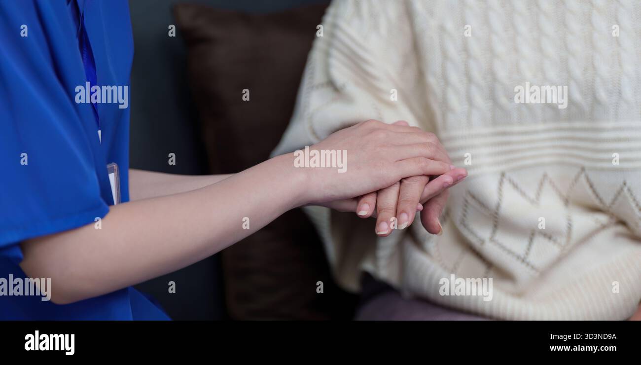 Compassionate nurse holding hands with elderly patient for emotional ...