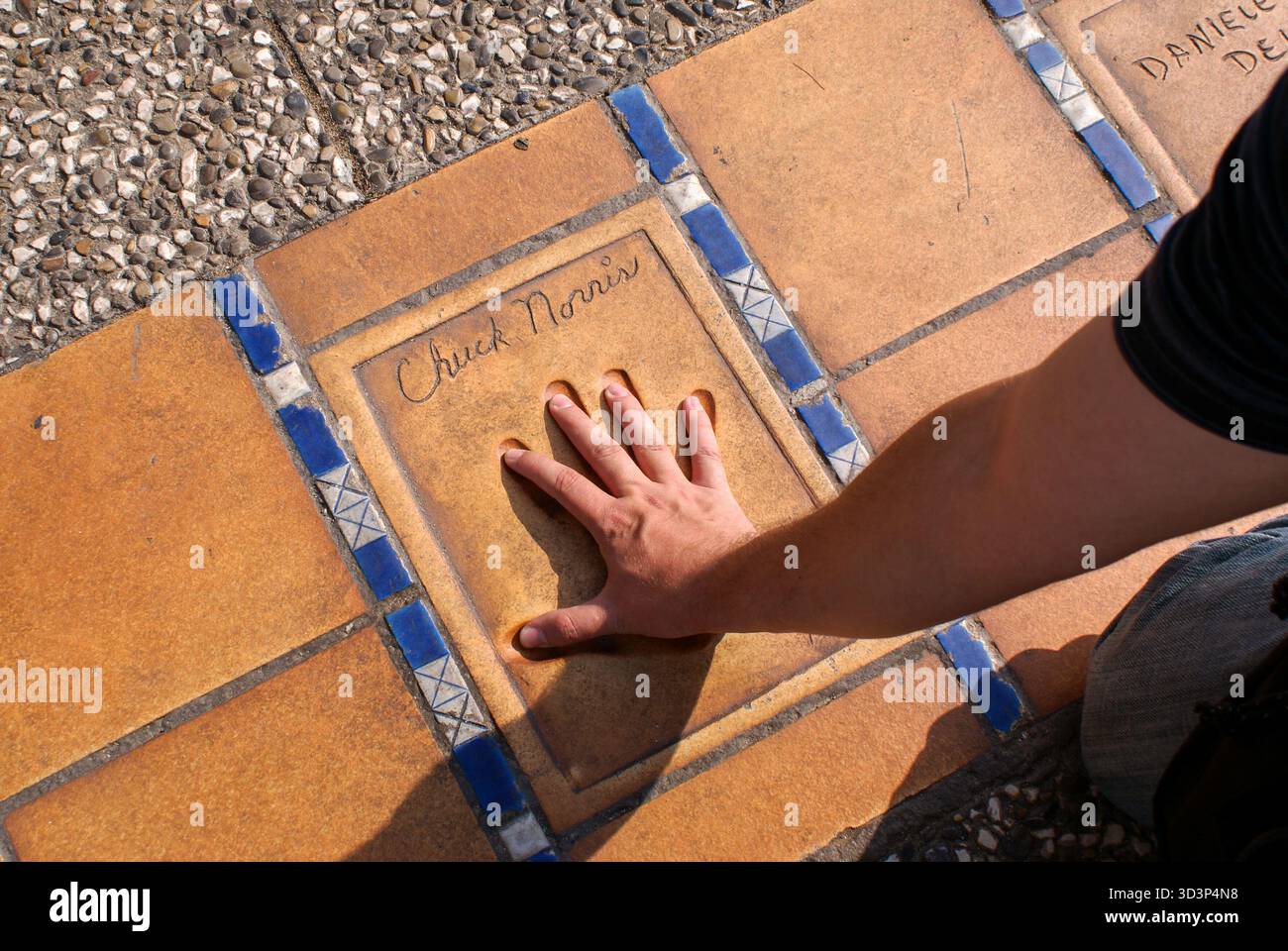Person's hand mirroring the celebrity handprint on a sidewalk tile ...