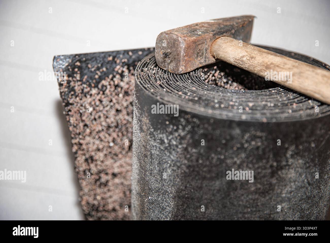 Hammer resting on black waterproofing roofing roll used for ...