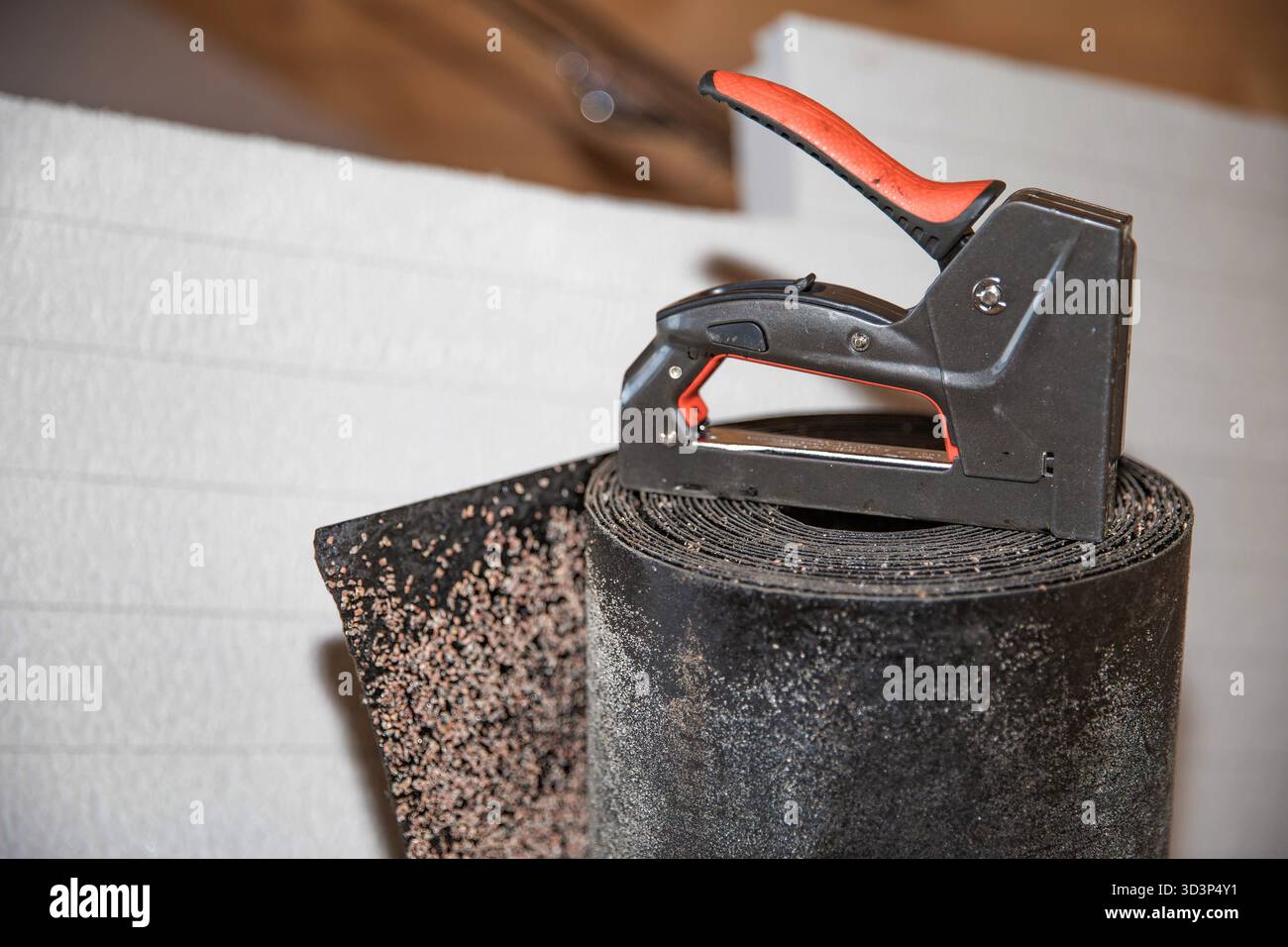 Construction stapler placed on rolled waterproofing roofing material ...