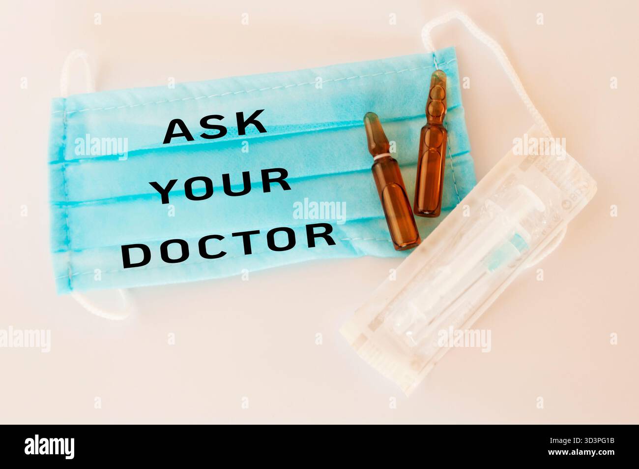 Medical mask featuring text, alongside vials and a syringe on a clean ...
