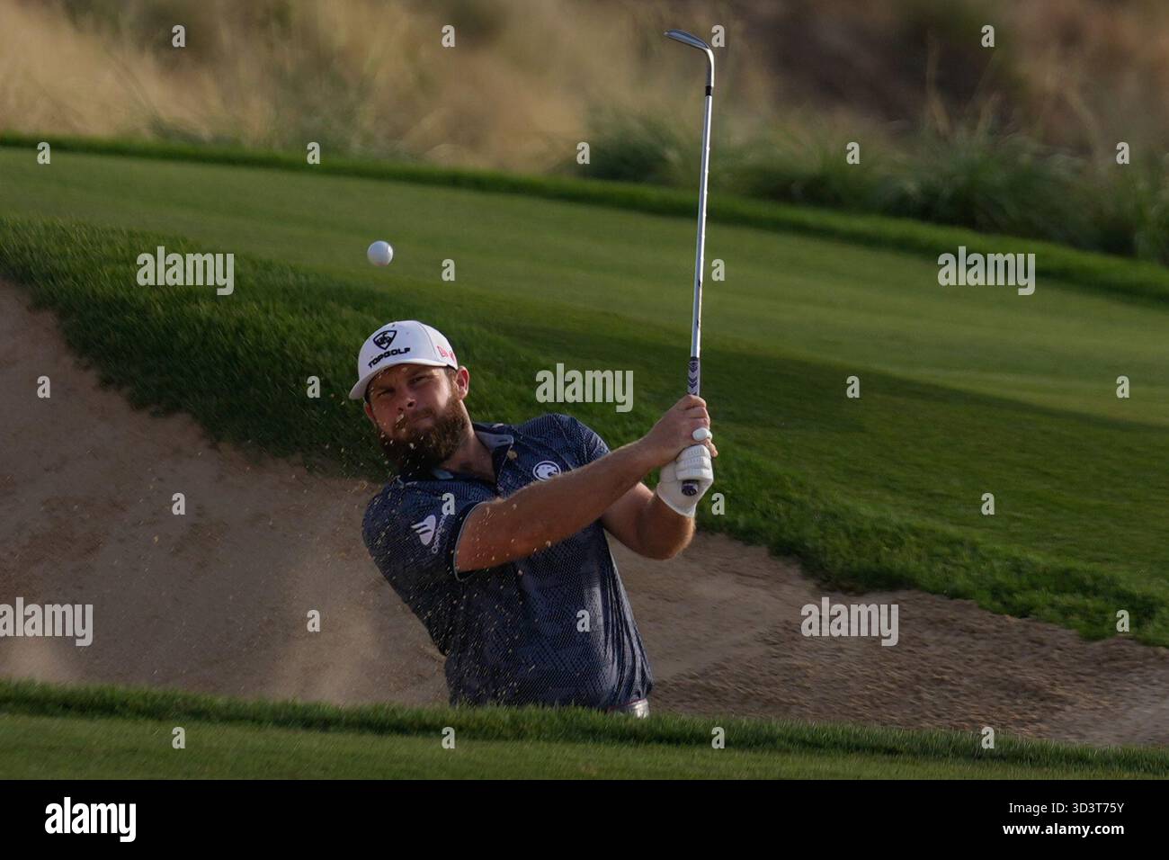 Tyrell Hatton of England hits a shot from a bunker on the 17th hole ...