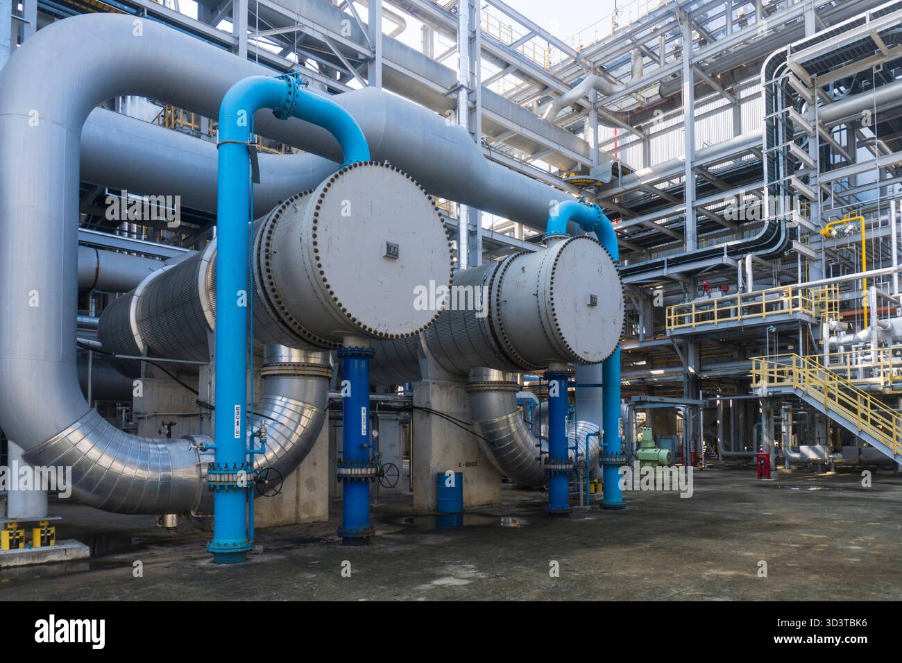 Large industrial plant with pipes and valves. The pipes are blue and ...