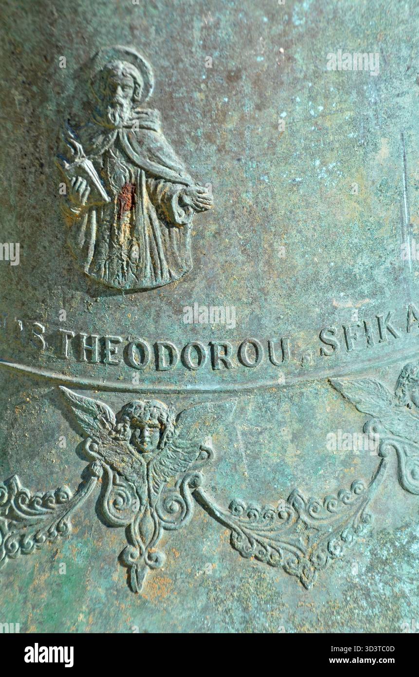Detail of a weathered bronze bell featuring a relief of a saint ...