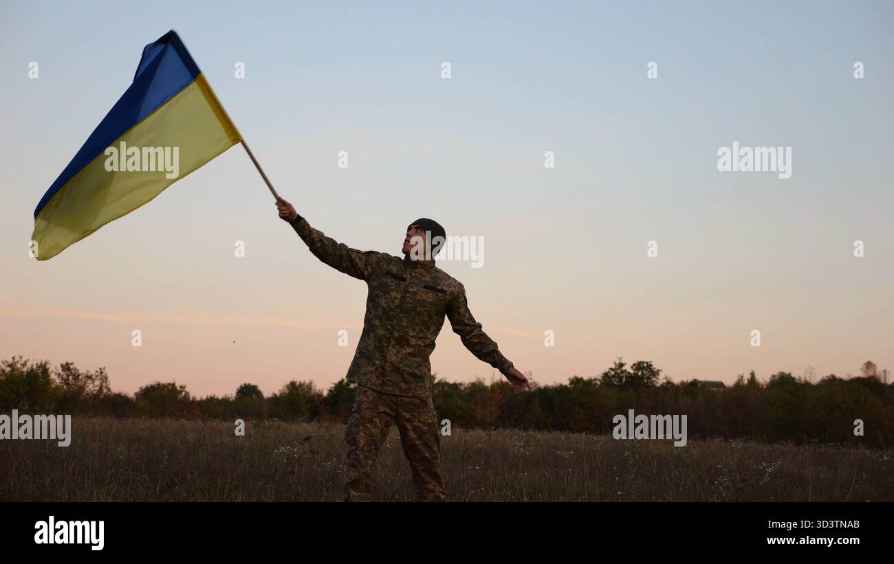 Male military waving blue-yellow banner on liberated territory occupied ...