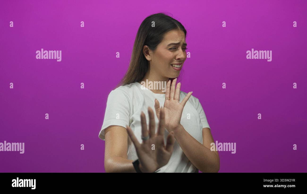 Young brunette woman pushing hands forward palms out in studio with ...