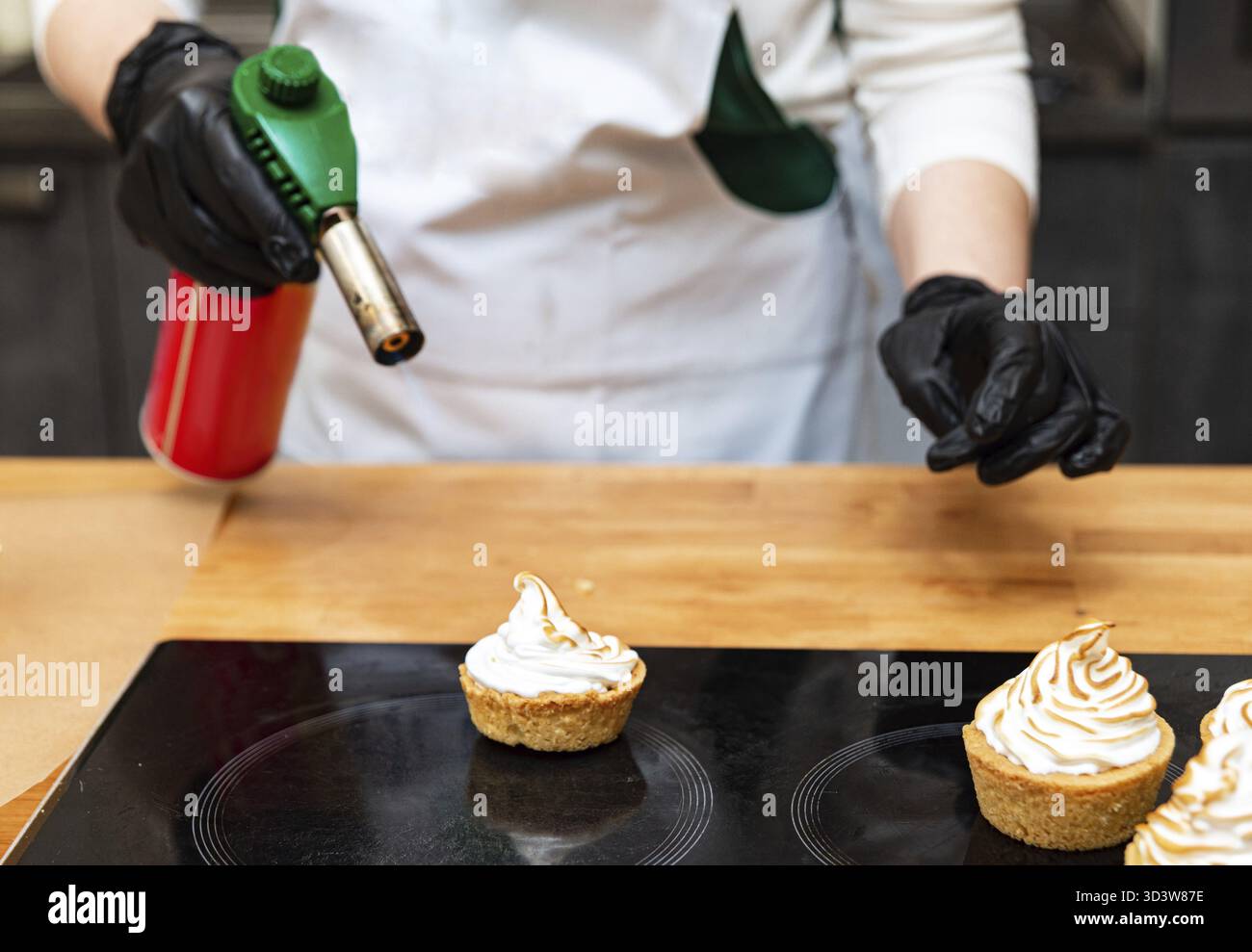 Food, Pastry chef using a blowtorch to toast meringue on top of small ...