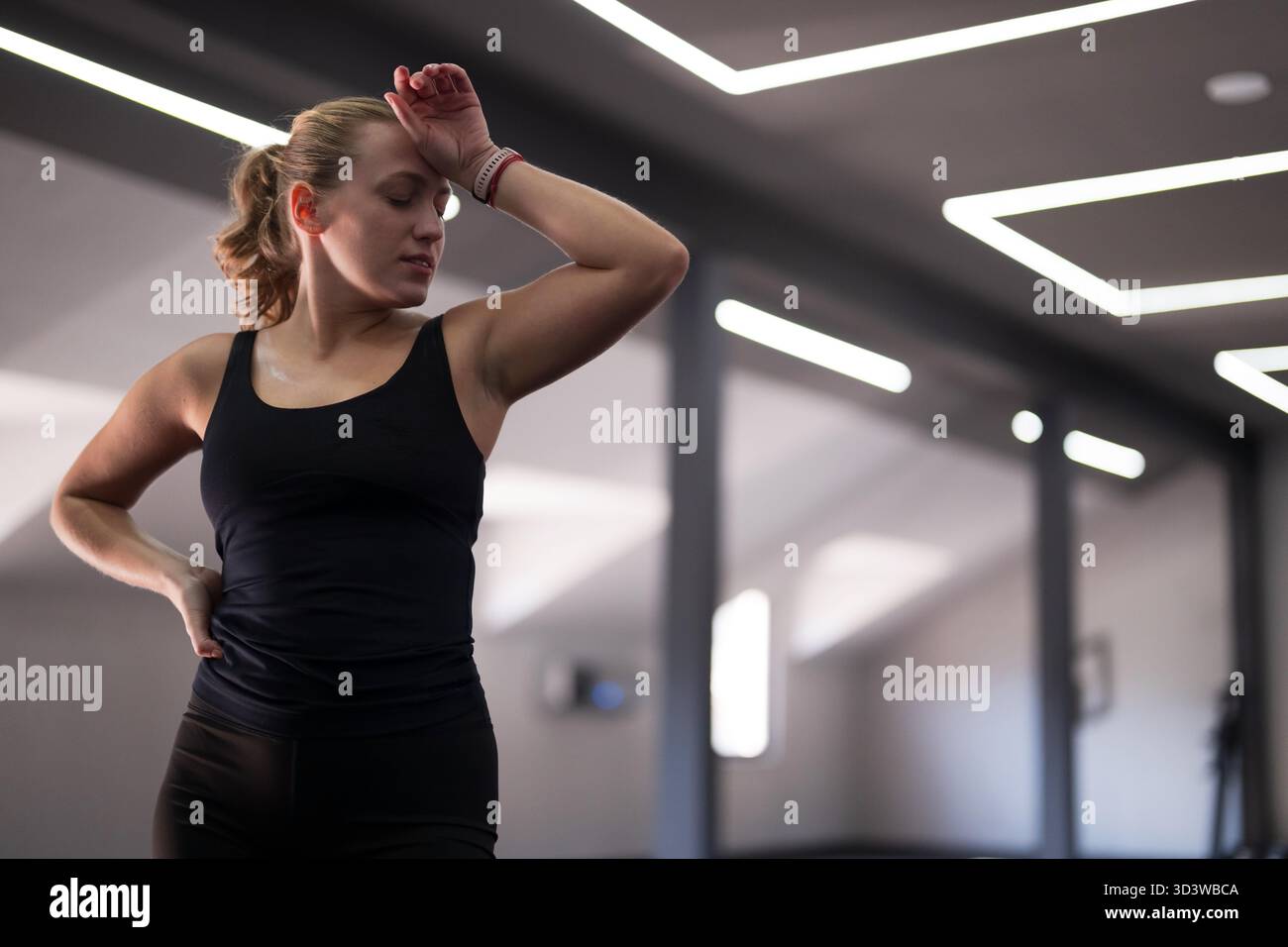 Fitness enthusiast takes a break during workout session in modern gym ...