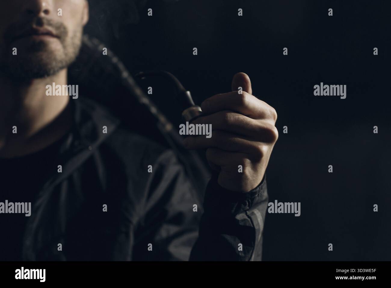 Man smokes smoking pipe against dark background. Back side lit profile ...